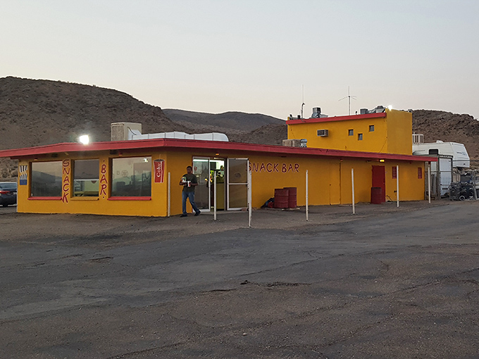 The vibrant yellow and red snack bar beckons with promises of buttery popcorn and nostalgic treats as dusk settles.