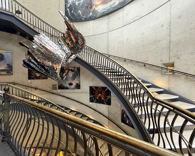 The sweeping staircase isn't just functional&mdash;it's a sculptural journey upward, with art suspended in mid-air like creative constellations.