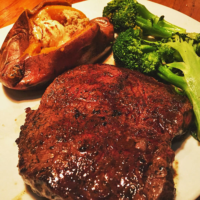 A perfectly seared steak shares the plate with a loaded baked potato and vibrant broccoli&mdash;the holy trinity of steakhouse satisfaction.