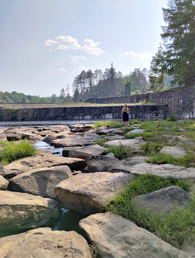 Where water meets stone in a geological handshake. The dam's outflow creates nature's perfect meditation spot for contemplating absolutely nothing.