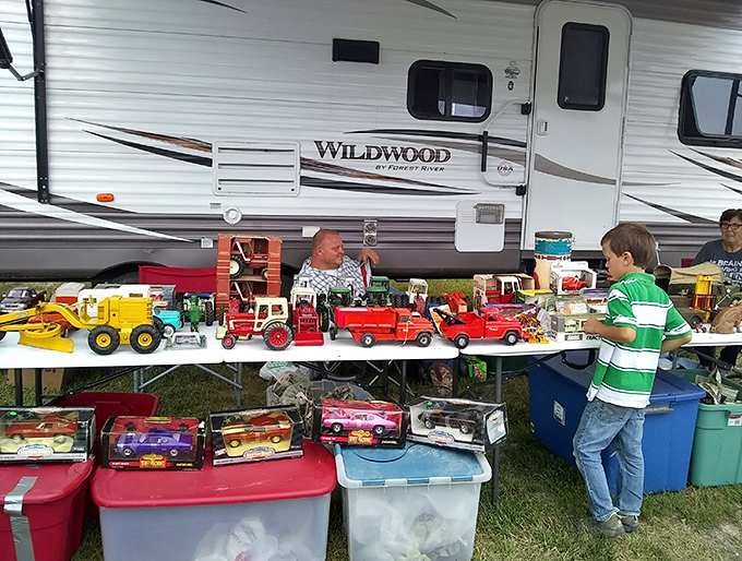 Childhood memories lined up for inspection! A young collector contemplates vintage toy trucks that once fueled the imaginations of previous generations. 