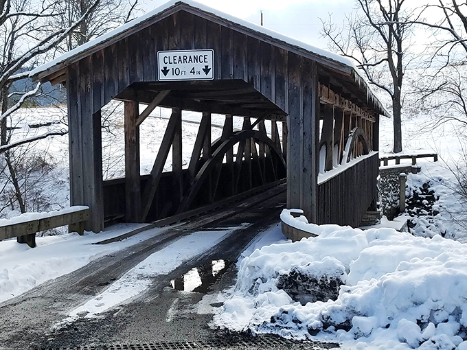 Winter transforms Knapp's into a scene straight from a holiday card. The clearance sign stands guard, ensuring modern vehicles respect this historical passage.