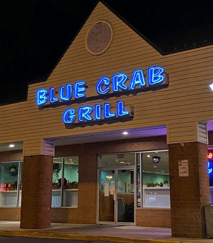 That neon blue crab sign glows like a beacon for seafood lovers. Simplicity outside, seafood magic inside.