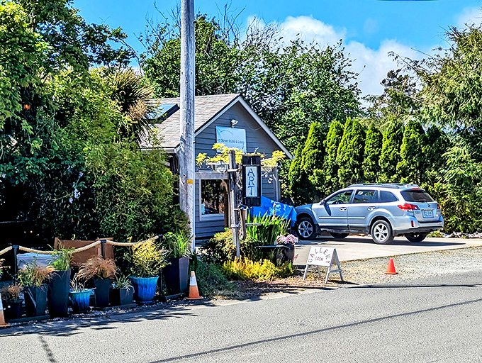 Tucked among towering evergreens, this charming blue gallery offers artistic treasures in a setting that feels more like a secret garden than a storefront.