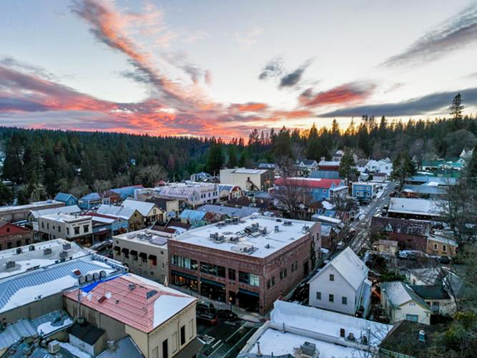 Sunset bathes Nevada City in golden light, revealing a patchwork of historic buildings nestled among towering pines like a Sierra Nevada snow globe.
