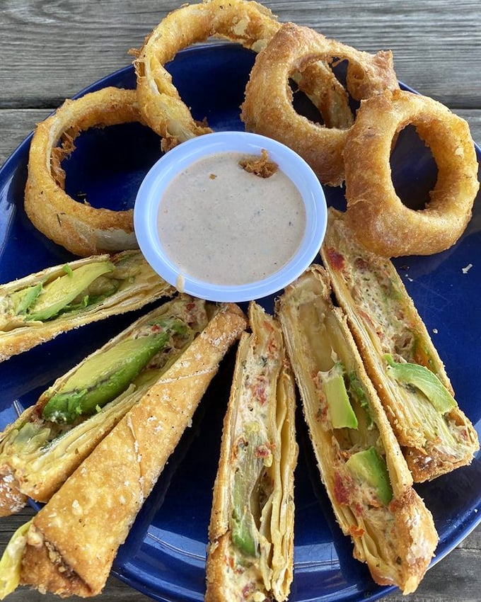 Avocado egg rolls and onion rings arranged like edible art—proof that beach food can transcend the ordinary.