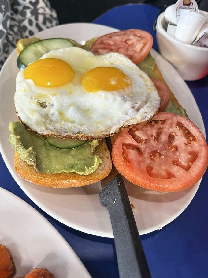 Avocado toast that actually fills you up! Two sunny-side-up eggs crown this open-faced breakfast royalty, with fresh tomatoes and cucumbers adding crunch.