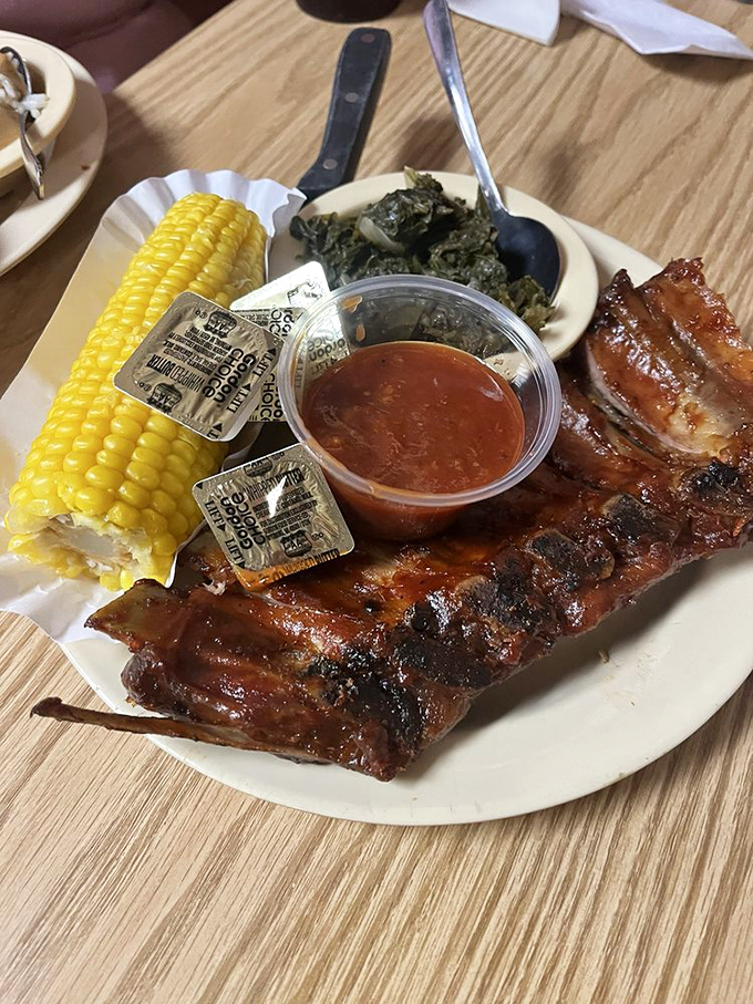 Barbecue ribs glistening with sauce, served alongside corn on the cob and collard greens&mdash;a holy trinity of Southern comfort that speaks directly to your soul.