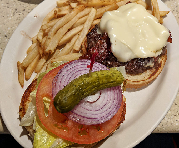 Not just any burger – a proper diner burger with the works. That pickle isn't garnish; it's an essential supporting character in this lunch drama.