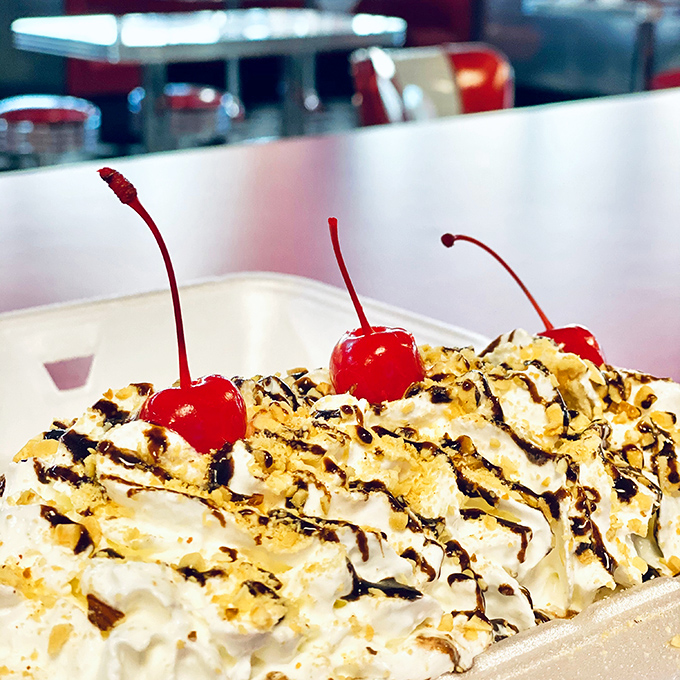 Three cherries standing guard over whipped cream mountains and chocolate rivers &ndash; dessert that demands respect and spoons.