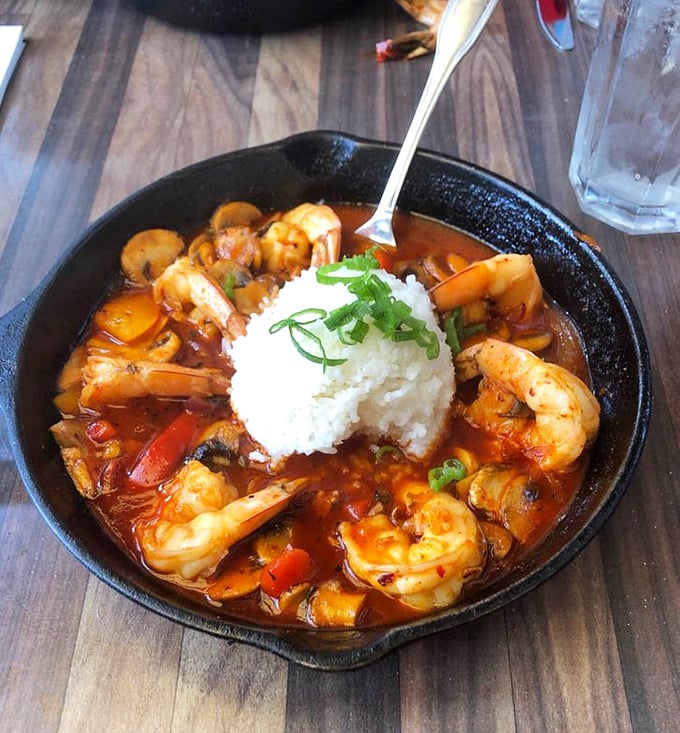 This sizzling skillet of BBQ shrimp with a crown of white rice isn't just dinner &ndash; it's a spicy, savory performance in a cast iron pan.