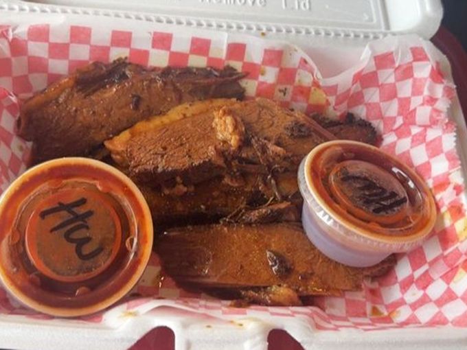 Brisket slices with that telltale pink smoke ring &ndash; nature's way of saying "patience rewarded" &ndash; flanked by sauce cups standing guard like delicious sentinels.
