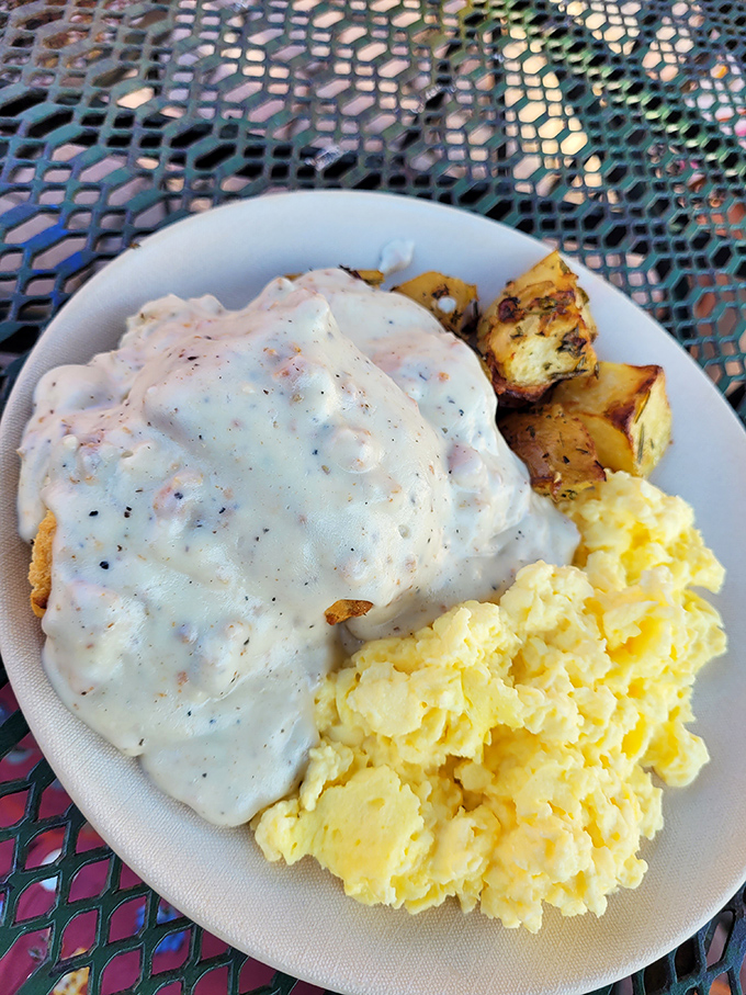 Comfort food nirvana: creamy sausage gravy cascading over a hidden biscuit, with perfectly scrambled eggs and herb-roasted potatoes standing by for reinforcement.