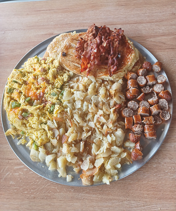 Breakfast nirvana achieved: scrambled eggs, home fries, pancakes, and bacon arranged like the four elements of morning happiness.