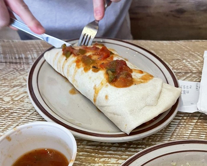 Behold the breakfast burrito in its natural habitat &ndash; a flour tortilla masterpiece topped with just enough chile to make you feel alive.