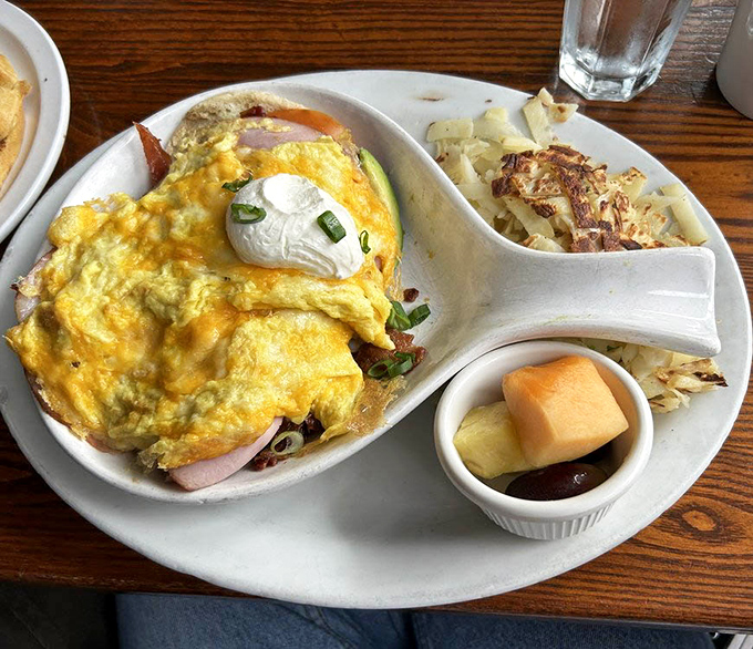 This isn't just breakfast, it's an omelet masterpiece &ndash; fluffy eggs embracing savory fillings, crowned with a dollop of sour cream and those crispy potatoes.