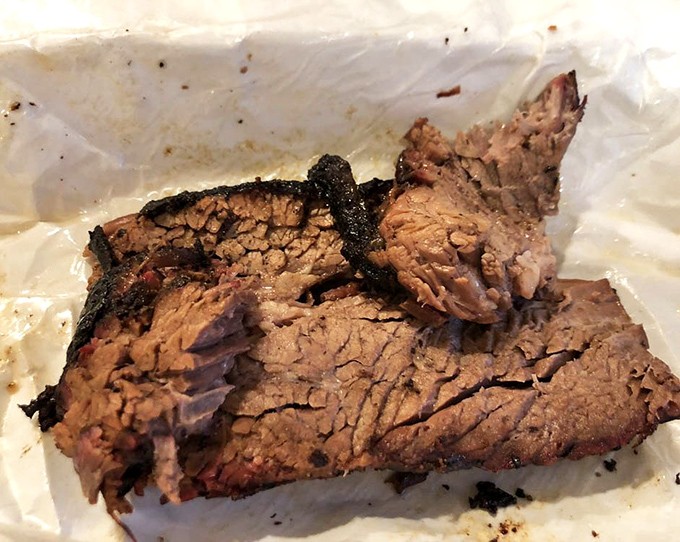 Brisket with a bark so perfect it deserves its own exhibition, revealing that pink smoke ring that makes barbecue aficionados go weak in the knees.