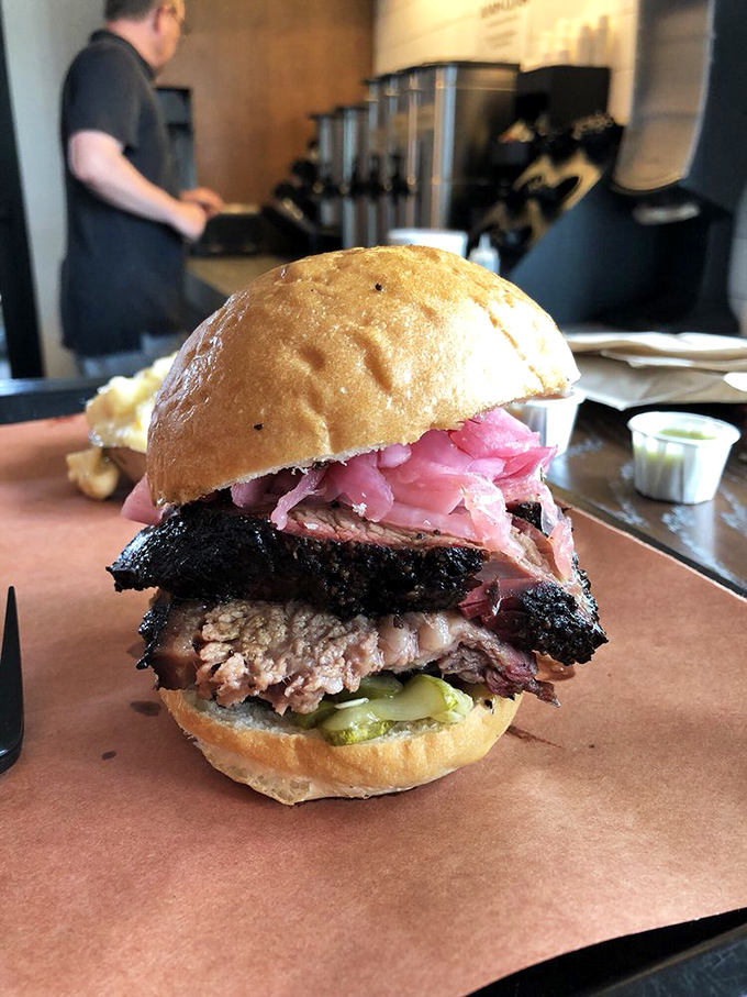Architecture in sandwich form: layers of smoky brisket, pink pickled onions, and tangy pickles create the Taj Mahal of Texas-meets-Carolina cuisine.
