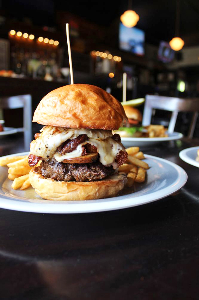 This isn't just a burger – it's a towering achievement of beef, bacon, and melted cheese that requires both hands, several napkins, and zero regrets.