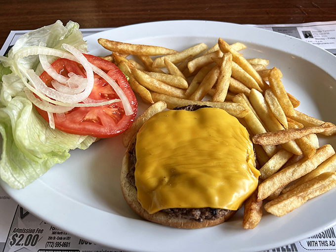 Behold the cheeseburger in its natural habitat – melty American cheese cascading down a substantial patty, with fries standing at attention nearby.