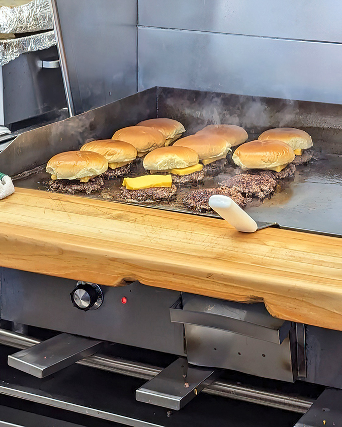 The sacred ritual of burger-making unfolds on the flat-top grill. Like watching Michelangelo paint, but with beef patties and melting cheese.
