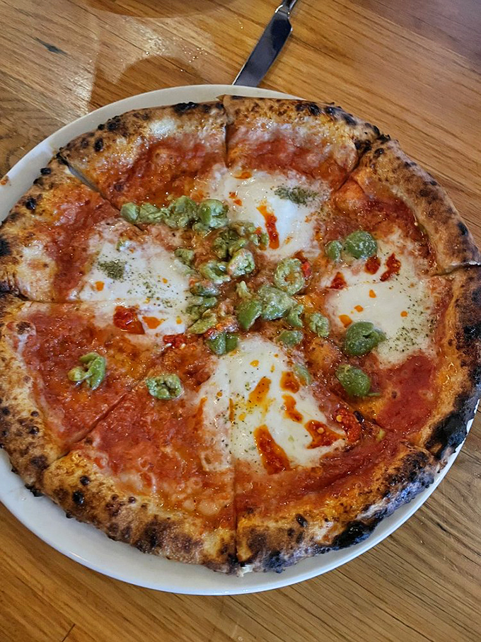 Pizza perfection emerges from the wood-fired inferno. That blistered crust with its leopard-spotted char is the diploma from the University of Naples.