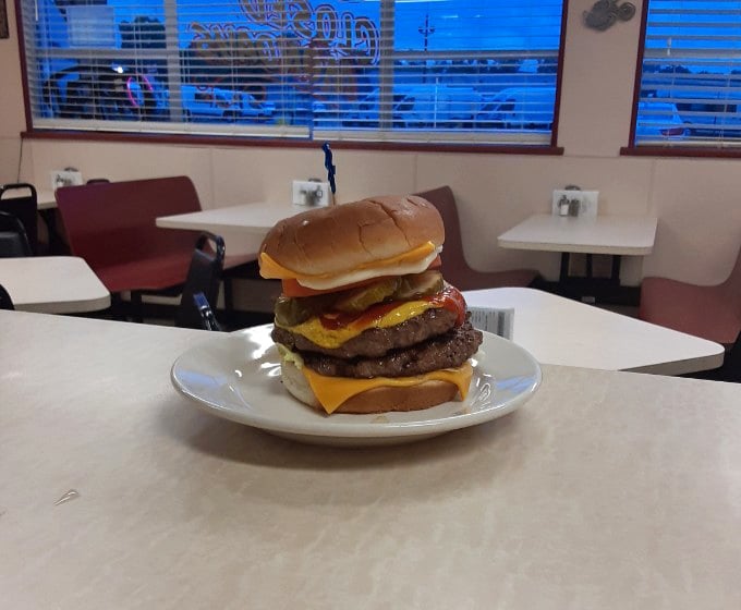 This towering burger defies both gravity and moderation. Not so much a meal as a dare wrapped in cheese and sandwiched between buns. 