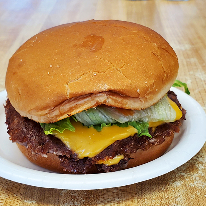 Behold the flat-top masterpiece: a thin-patty cheeseburger with those coveted crispy edges that extend beyond the bun&mdash;what burger aficionados reverently call "meat lace."