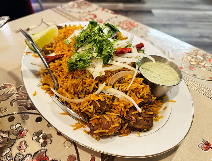Chicken biryani arrives like edible architecture: layers of saffron rice, tender meat, and centuries of culinary wisdom.