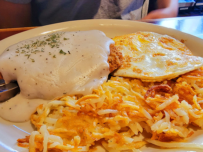Country gravy cascading over golden hash browns like a comfort food waterfall. This is the breakfast equivalent of a warm hug from your favorite aunt.
