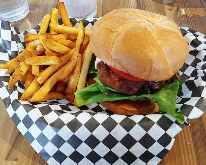 A burger that could convert carnivores, nestled in a pillowy bun with crisp lettuce and tomato, flanked by golden fries standing at attention.