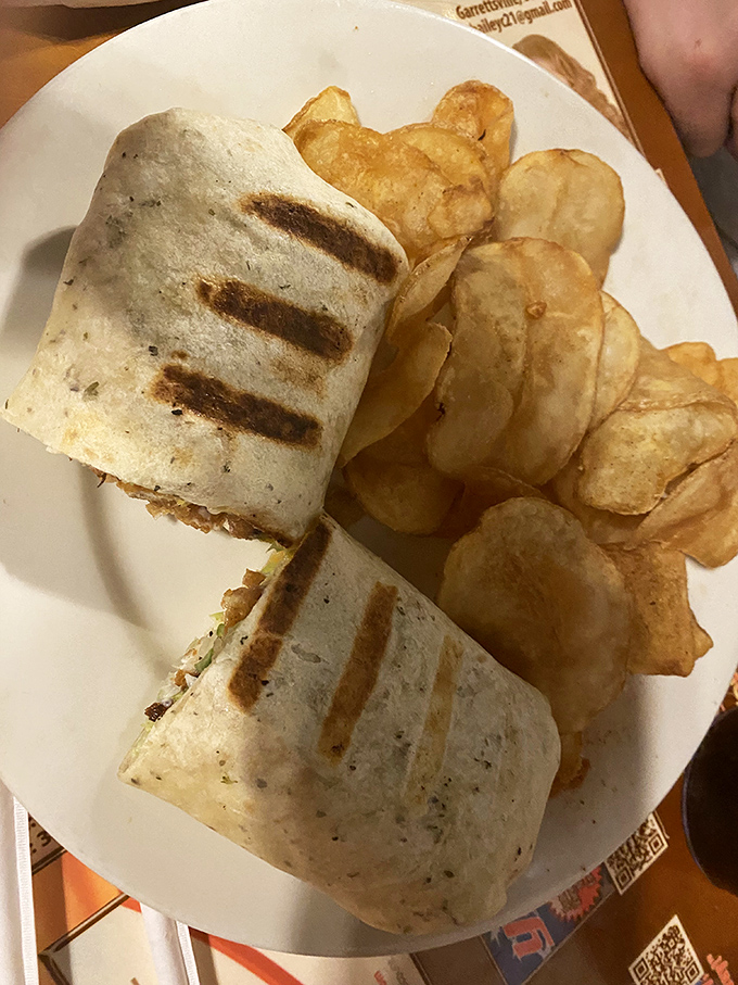 A wrap so perfectly grilled it deserves its own trophy, flanked by house-made chips that crunch loud enough to turn heads three tables over.