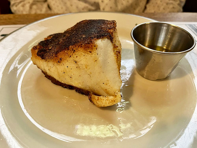The Chilean sea bass arrives with a perfect sear, its pearly white flesh promising the kind of buttery, flaky experience that creates lifelong cravings.