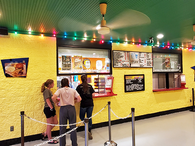 The vibrant yellow walls and colorful string lights of the concession area create a festive atmosphere that's half movie theater, half county fair.
