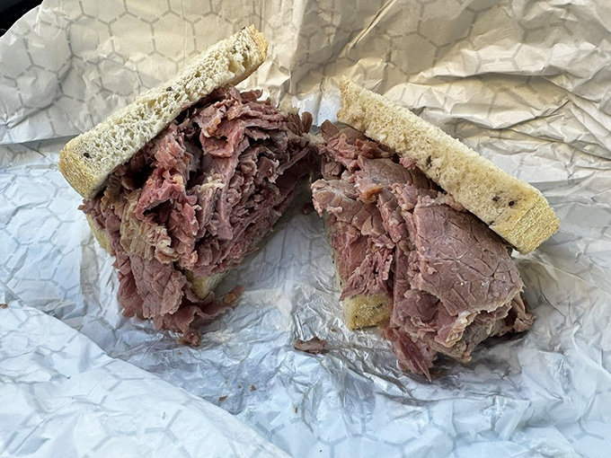 Behold the corned beef sandwich in its natural habitat, piled high enough to require architectural engineering.