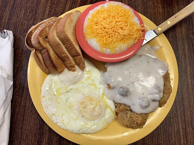 Country fried steak swimming in creamy gravy alongside sunny-side-up eggs and toast. Breakfast architecture that would make Frank Lloyd Wright weep with joy.