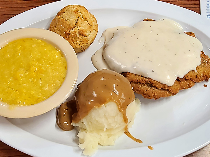 Country fried steak smothered in pepper gravy alongside creamy grits and a biscuit—the holy trinity of Southern breakfast indulgence.
