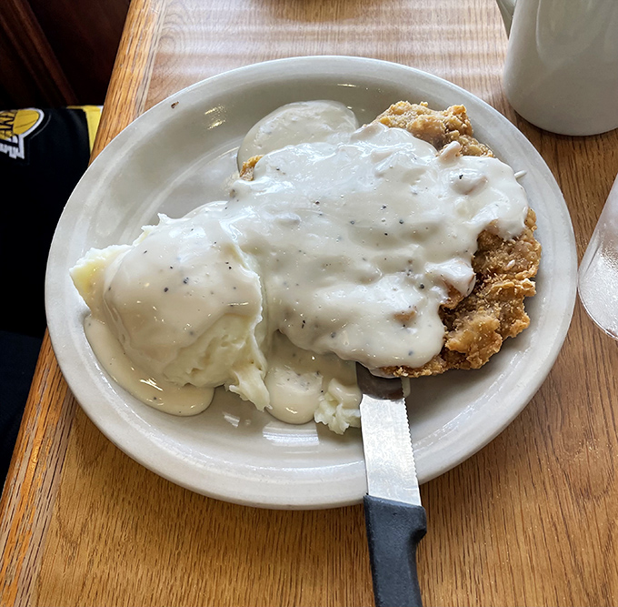 Country fried steak swimming in creamy gravy alongside mashed potatoes &ndash; the kind of plate that makes diets wave white flags of delicious surrender.