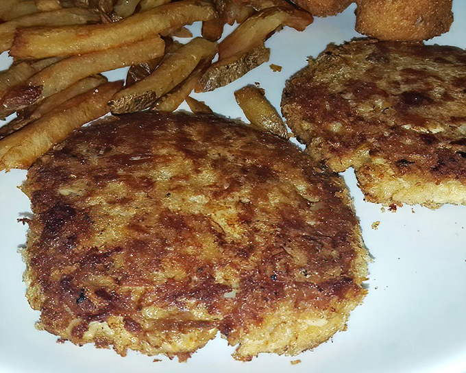 These crab cakes aren't trying to win beauty contests; they're too busy delivering honest flavor with every crispy-edged, savory bite alongside those perfectly golden fries.