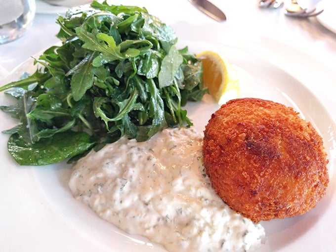 The golden-brown crab cake sits proudly beside its creamy sauce companion &ndash; a perfect marriage that would make even the most committed bachelor consider settling down.