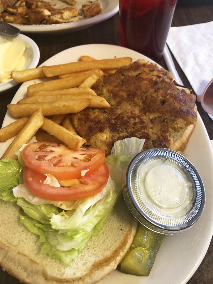 The holy trinity of diner perfection: golden-brown crab cake, crispy fries, and a pickle spear standing guard. Lunch doesn't get more Delaware than this.