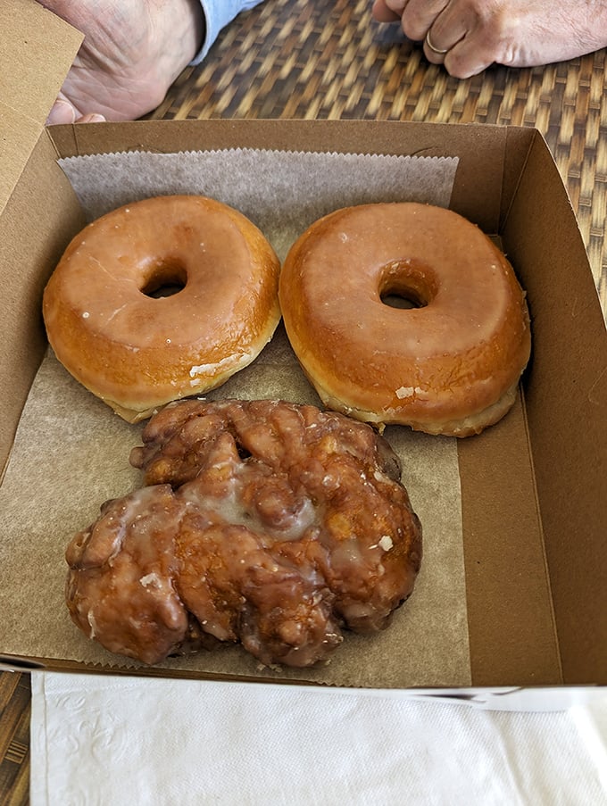 The holy trinity of breakfast indulgence: two glazed donuts and what appears to be an apple fritter that could make your cardiologist weep.