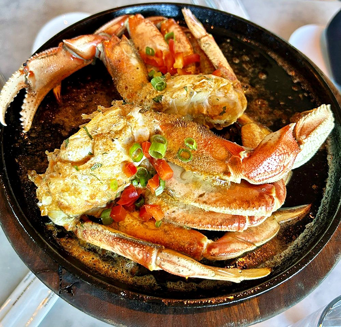 Dungeness crab, sizzling in garlic sauce, arranged like a work of art. This isn't just dinner; it's the reason stretchy pants were invented.