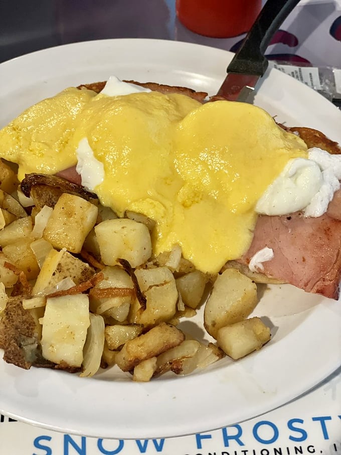 Eggs Benedict done right: a golden hollandaise blanket tucked over Canadian bacon and poached eggs, with home fries playing the perfect supporting role.