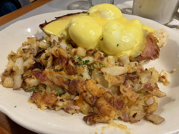 Eggs benedict over crispy hash browns with hollandaise that cascades like a delicious yellow waterfall&mdash;breakfast engineering at its finest right here.