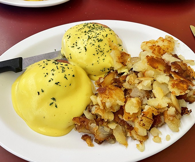 These eggs Benedict aren't just breakfast; they're a masterclass in hollandaise perfection with home fries playing the perfect supporting role.