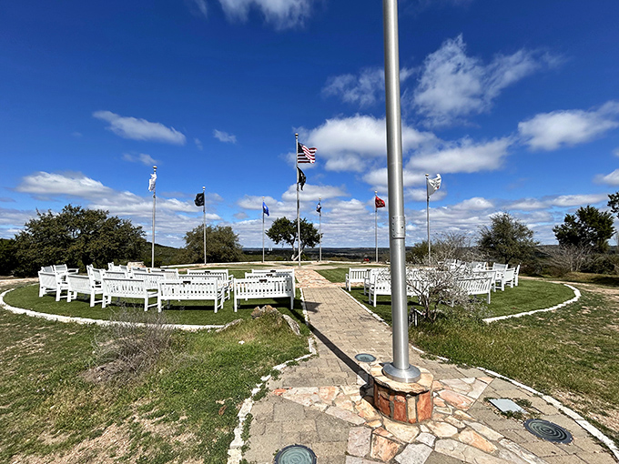 White benches arranged in perfect circles create an outdoor sanctuary where flags flutter stories of heritage against endless Hill Country skies.