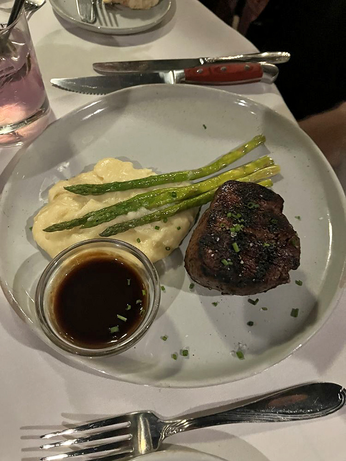 Filet mignon, mashed potatoes, and asparagus&mdash;the holy trinity of steakhouse perfection. That sauce cup is small but mighty, like Danny DeVito.