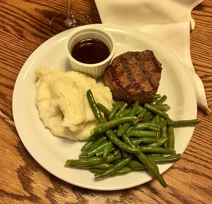 The filet mignon arrives like a dignified gentleman &ndash; compact, well-dressed, and surrounded by excellent company of mashed potatoes and green beans.