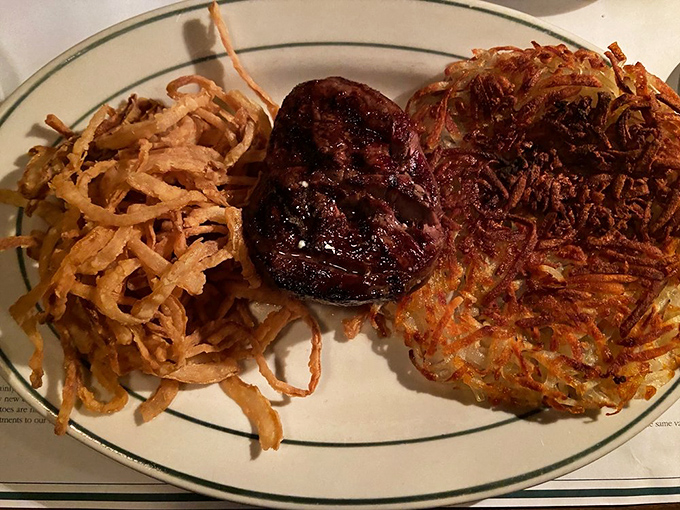 The holy trinity of steakhouse perfection: a juicy filet, golden hash browns, and those famous onion rings that could double as delicious jewelry.